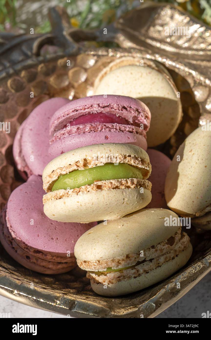 Colorful macarons are elegantly placed in a gold leaf bowl, accompanied ...