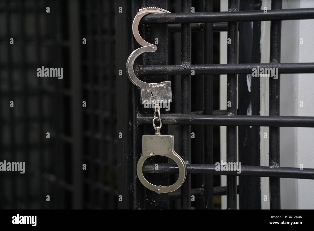 Handcuffs are hanging on the bars of the door of the detention center ...