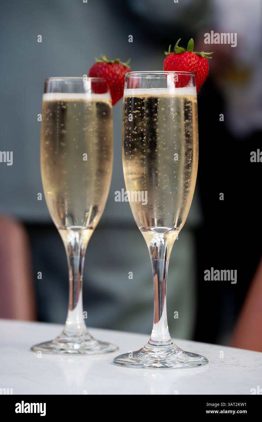 Two champagne flutes with strawberries on rim, filled with bubbl Stock ...