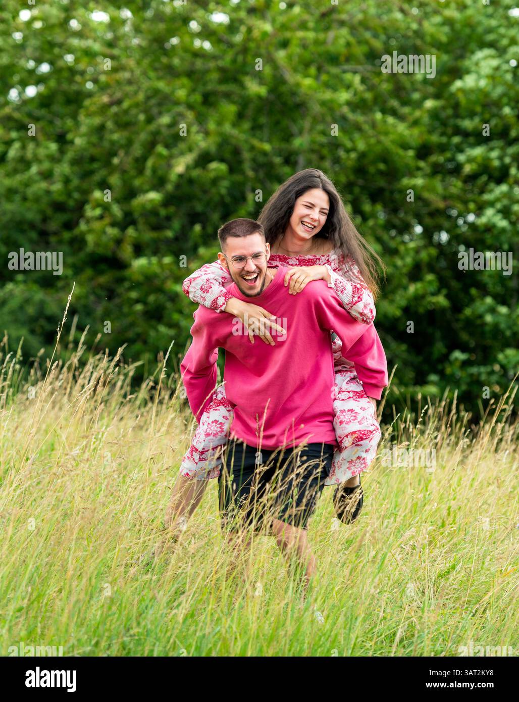 Gen Z couple having fun in nature, man piggybacking the woman in tall ...