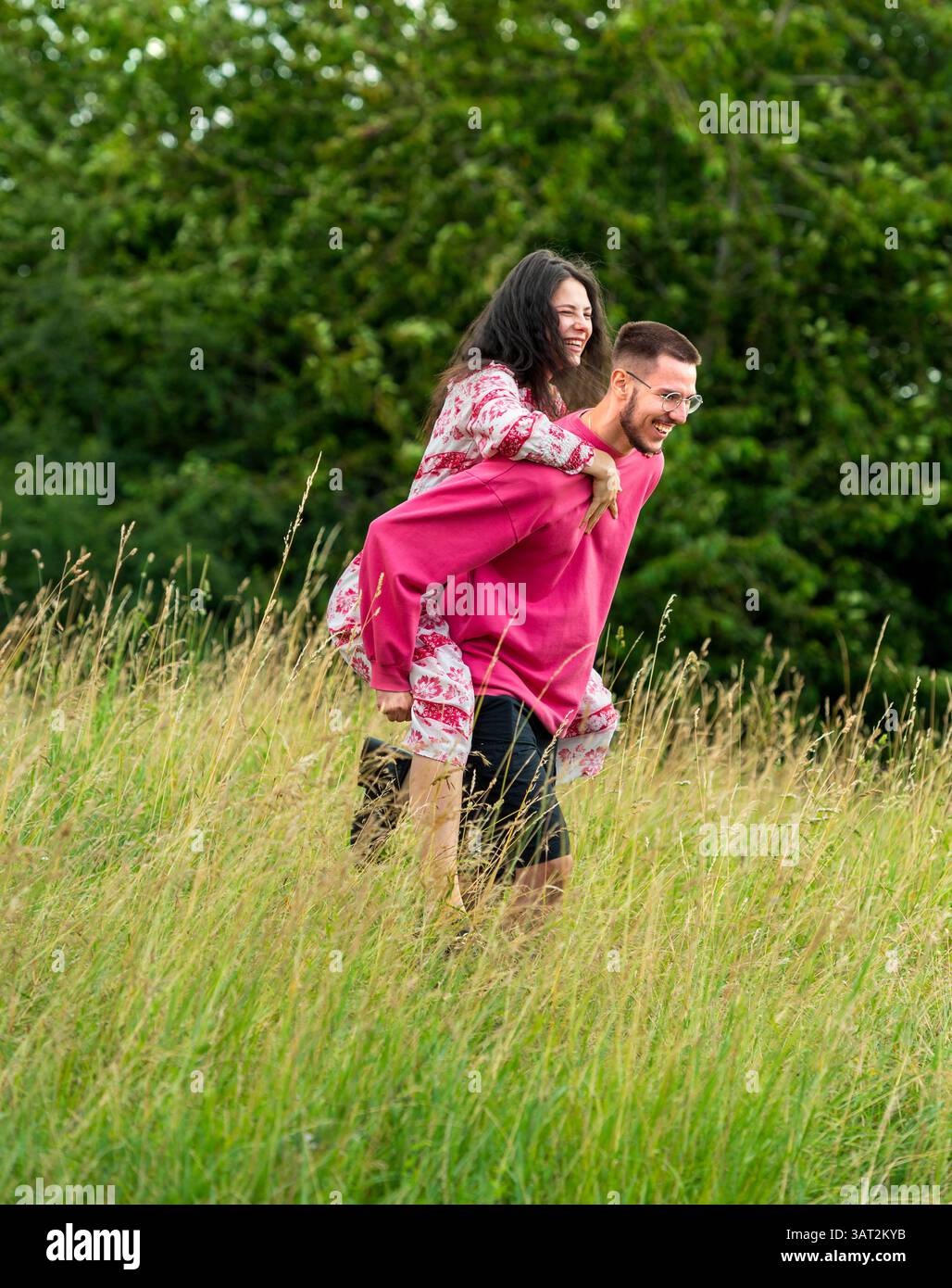 Gen Z couple having fun in nature, man piggybacking the woman in tall ...
