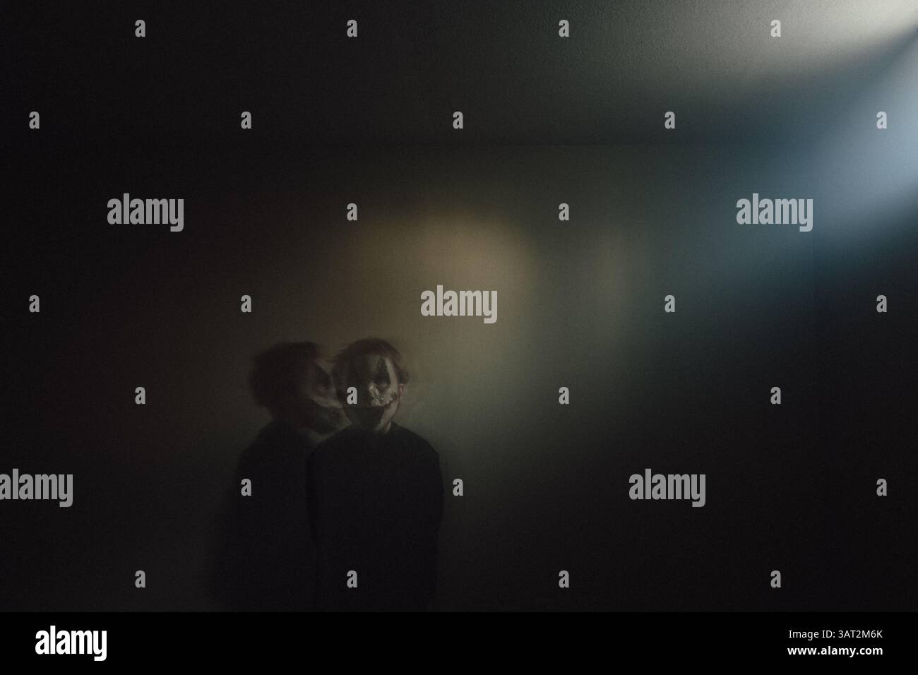 Long exposure of horror clown boy standing in spooky light in basement ...