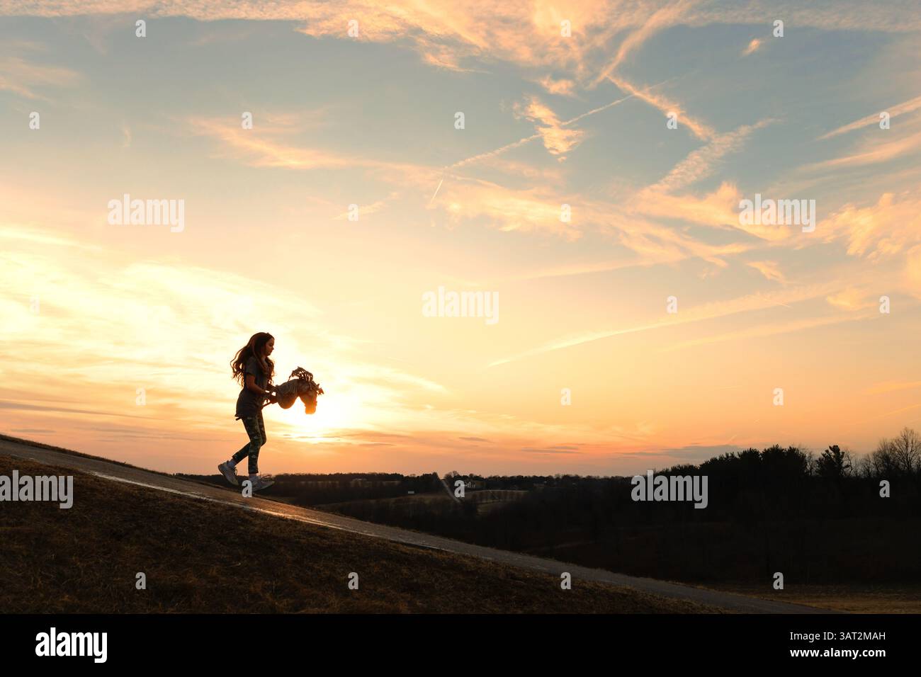 Side view tween girl riding stick horse outdoors sunset Stock Photo - Alamy