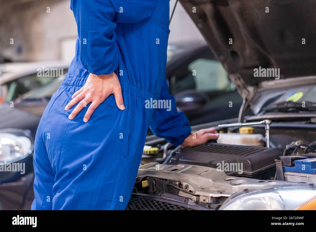Rear view of unrecognizable man wearing mechanic holding his lower back ...