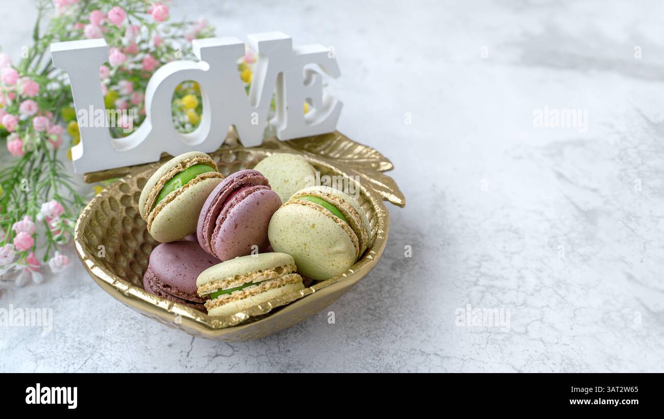 Colorful macarons are elegantly placed in a gold leaf bowl, accompanied ...