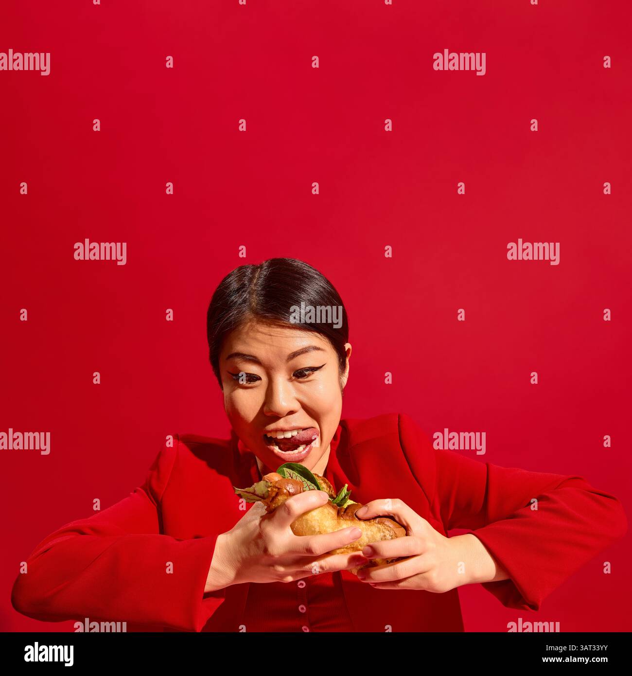 Woman in red joyfully prepares to bit delicious hot dog against bold ...