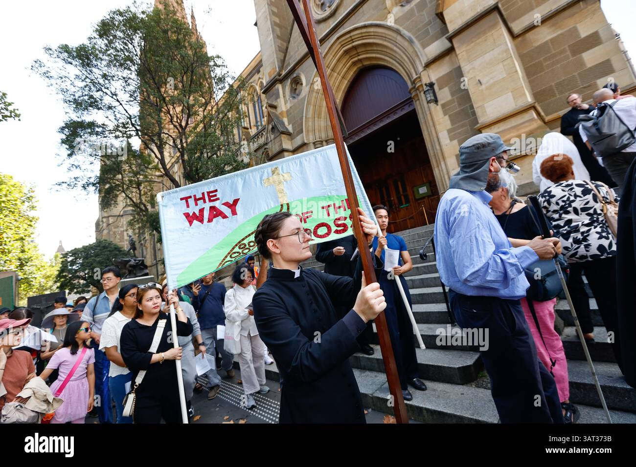 Reverend holds a wooden cross during the Stations of the Cross ...