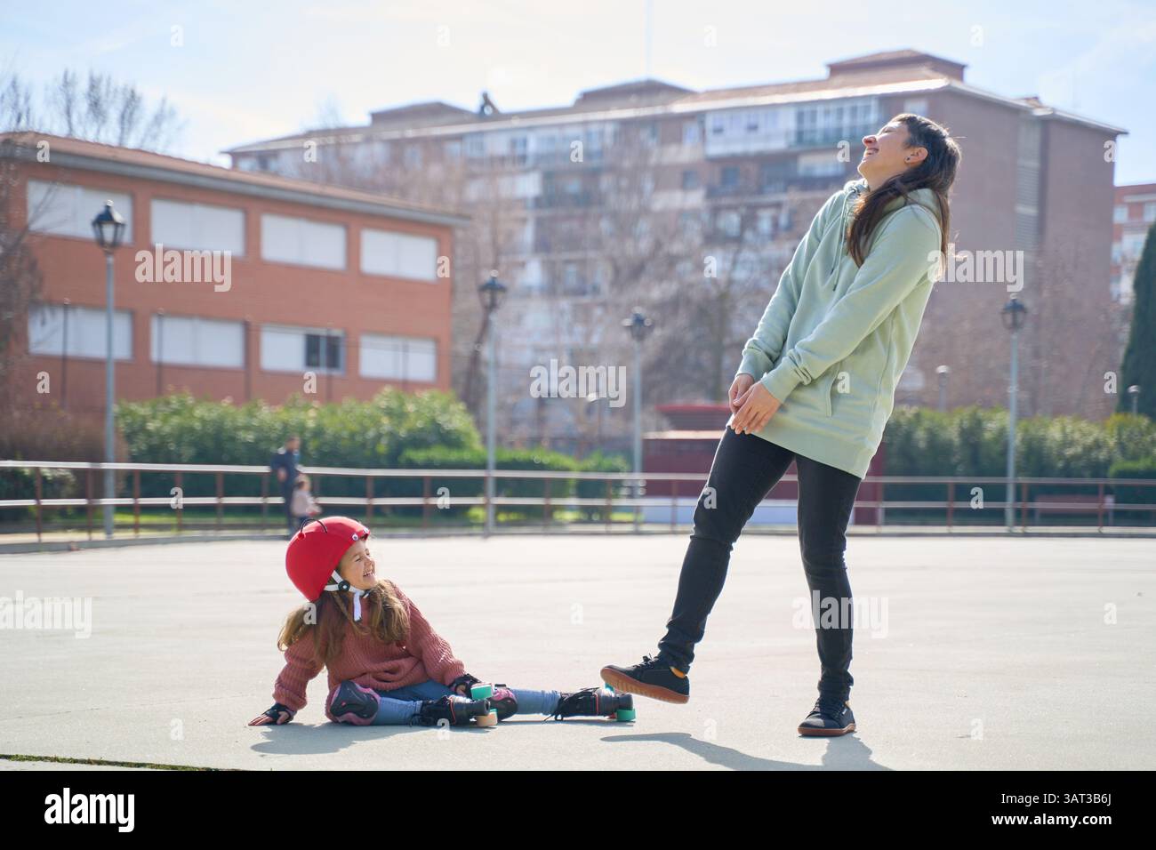Mom and daughter having fun in urban park, the girl has fallen with her ...