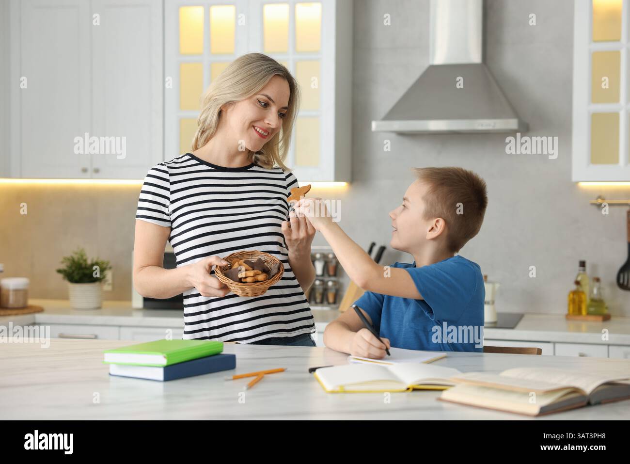 Mother and son eating cookies while doing homework indoors Stock Photo ...