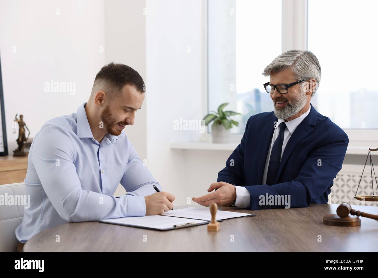 Client signing notarial paperwork during meeting with lawyer at wooden ...