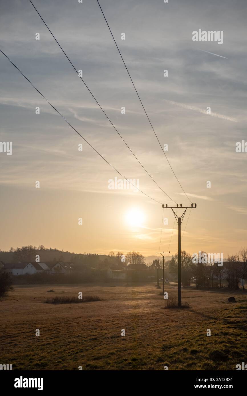 Electric poles and wires at sunset over countryside Stock Photo - Alamy