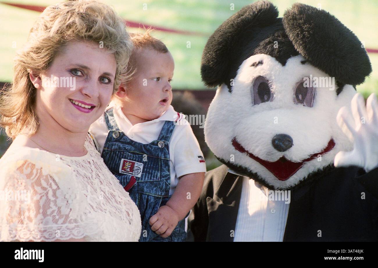 Mother with baby posing with person dressed as Mickey Mouse in ...