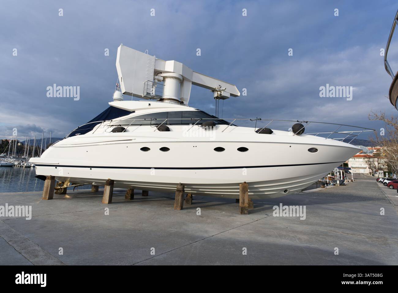 A sleek white yacht, elevated on wooden supports, stands prominently on ...