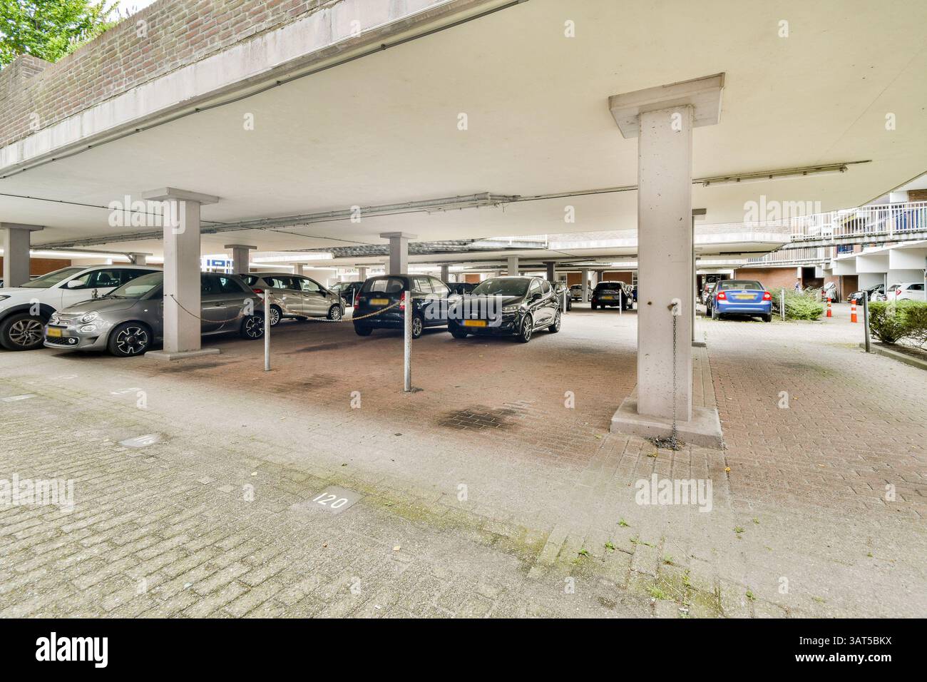 A spacious multi-level parking garage showcasing several parked cars in a well-lit area. The ...