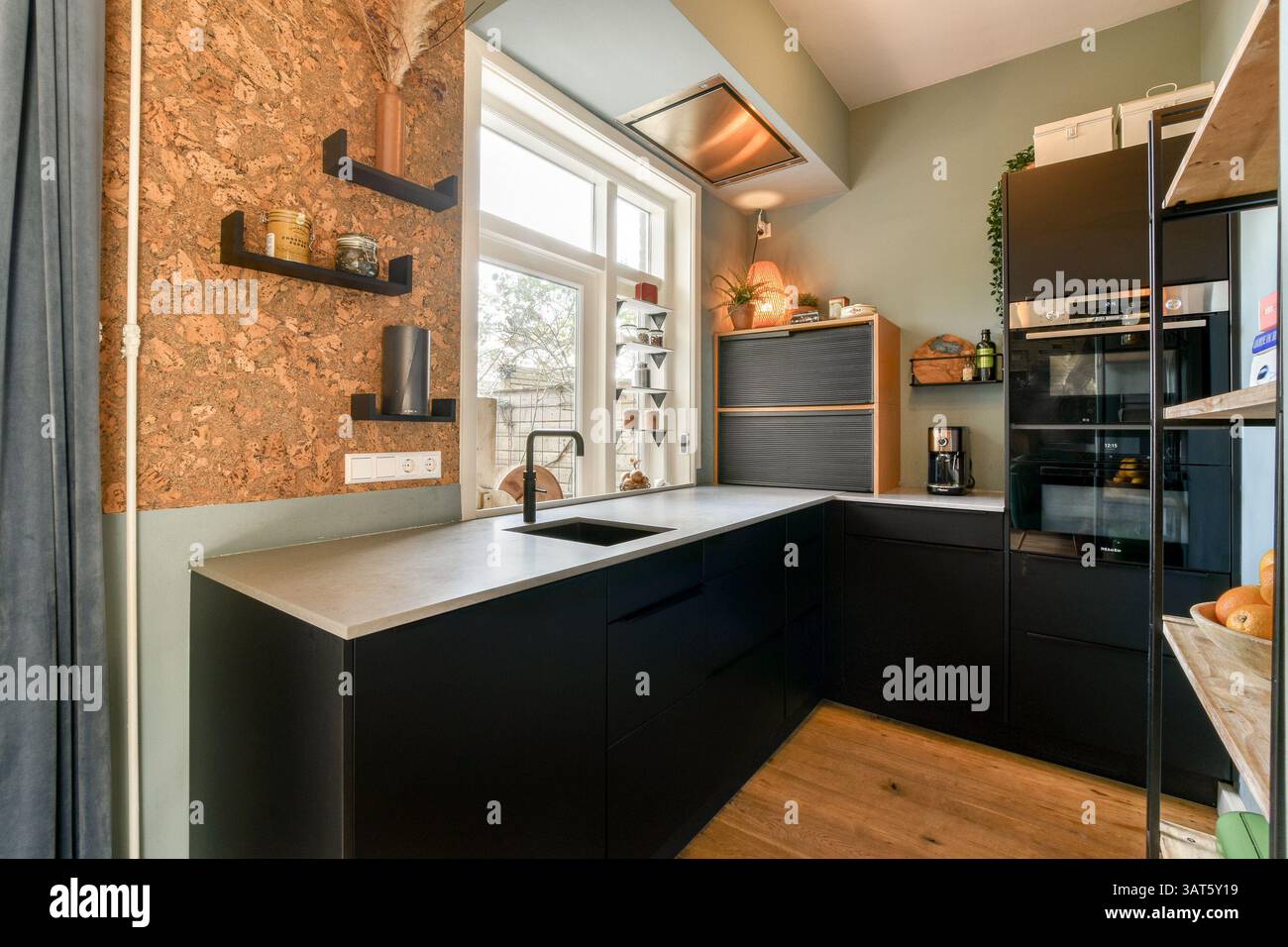 A stylish kitchen featuring sleek black cabinetry, a metallic ...
