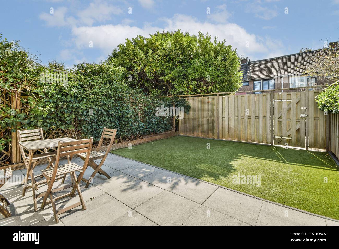 This backyard features lush greenery and a simple seating area ...