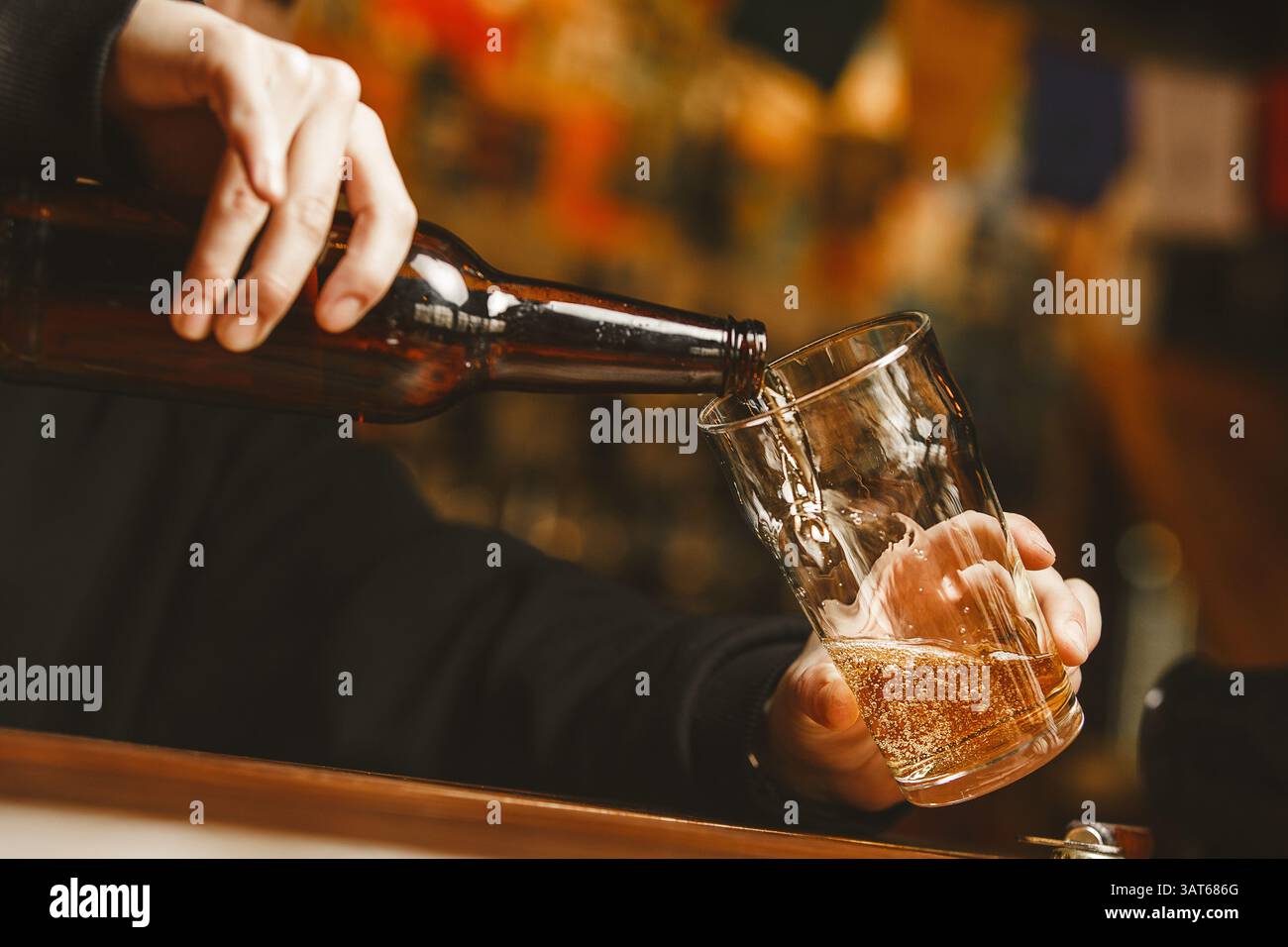 Bartender Pouring Beer From Bottle Into Glass at Wooden Counter Stock ...
