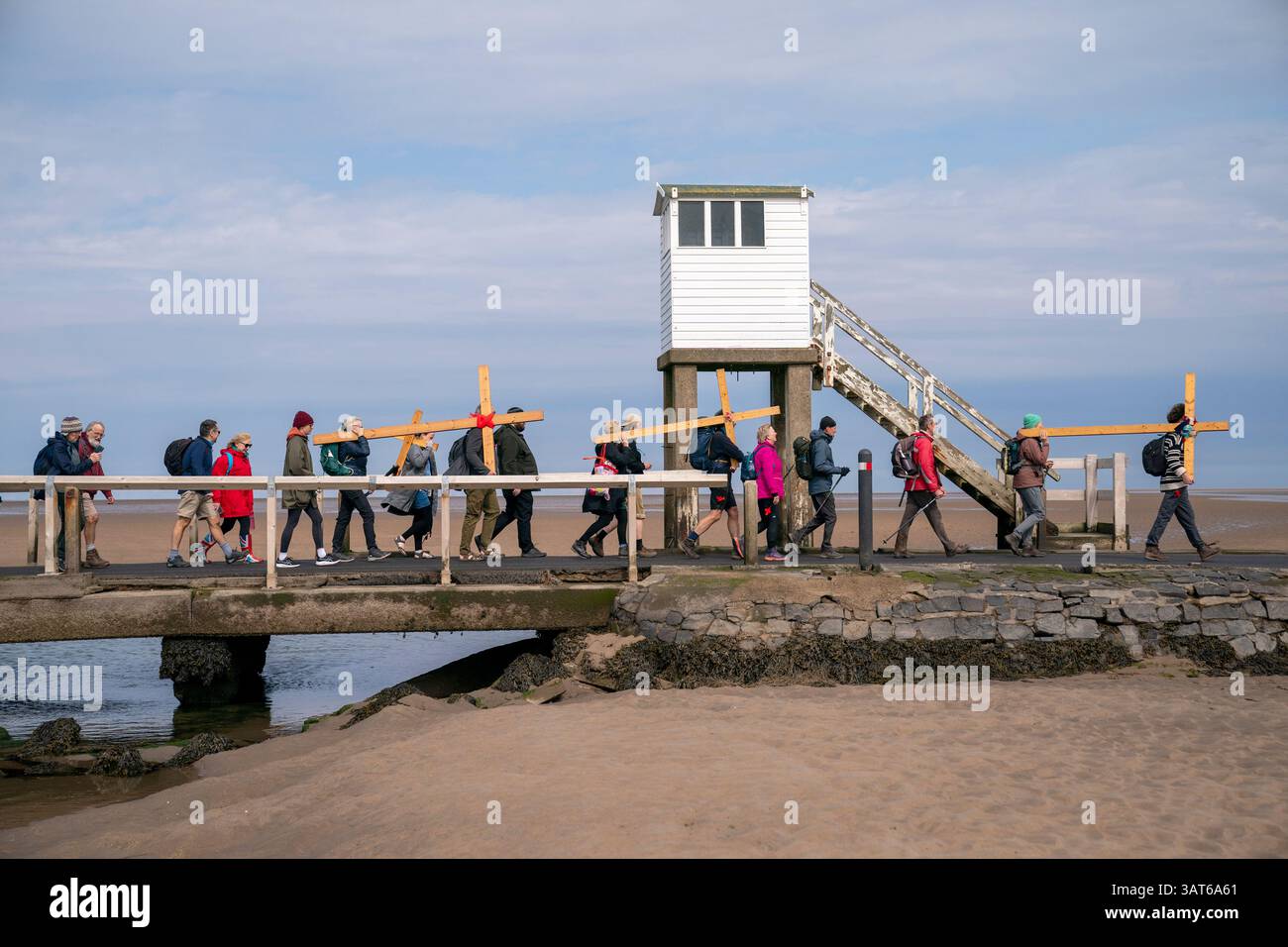 Pilgrims carrying wooden crosses cross the sands at low tide to the ...