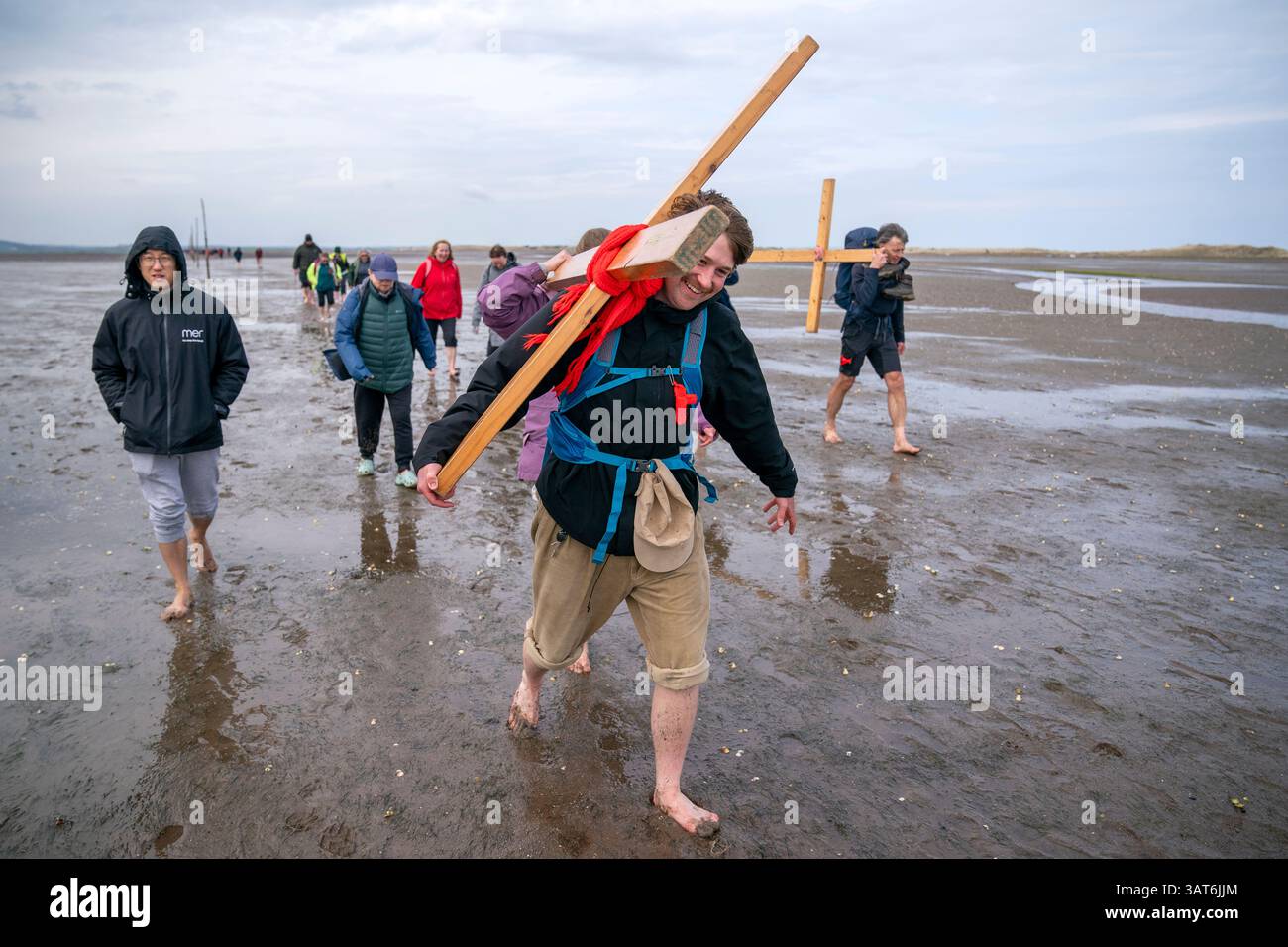 Pilgrims carrying wooden crosses cross the sands at low tide to the ...