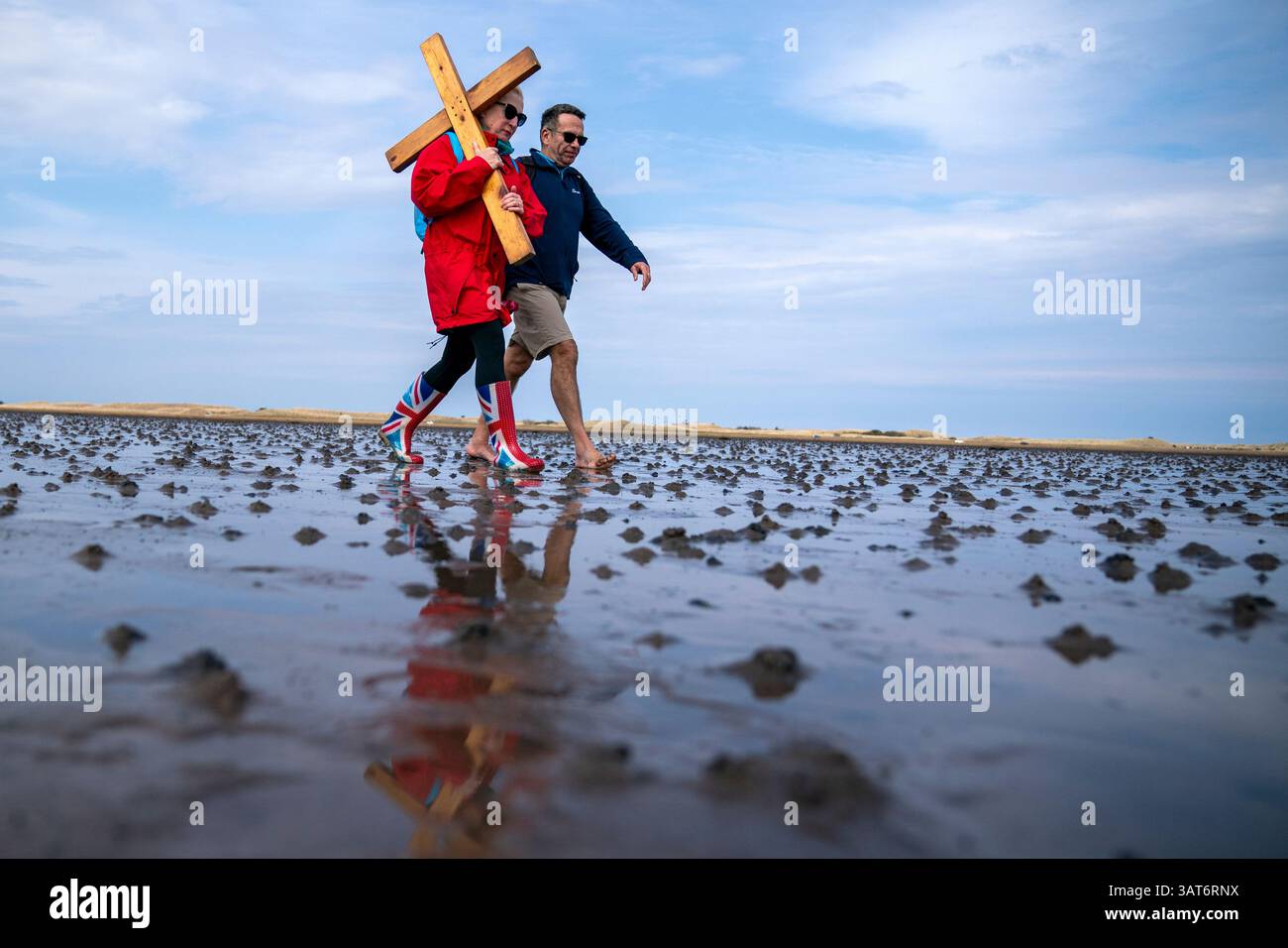 Pilgrims carrying wooden crosses cross the sands at low tide to the ...
