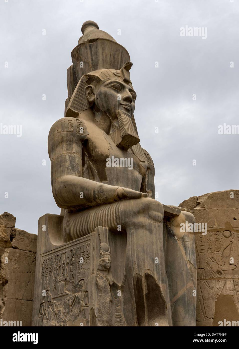 A large ancient statue of a pharaoh, seated with a headdress and ...
