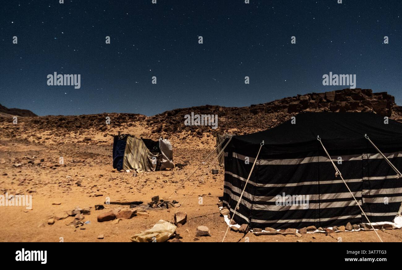 A serene desert landscape at night featuring tents under a starry sky ...