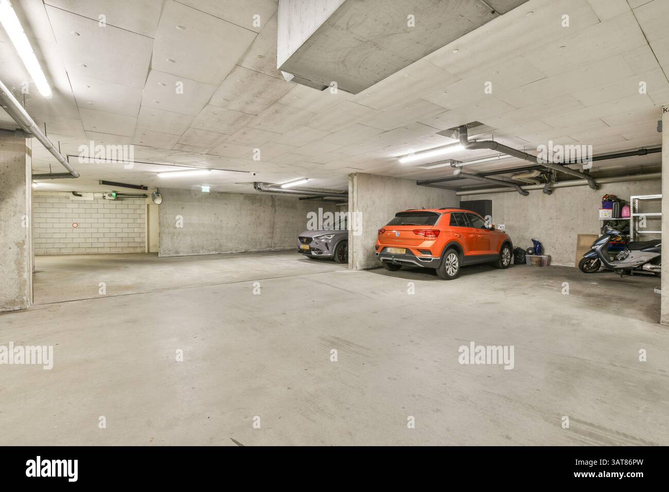 A spacious and well-lit underground parking garage featuring two parked ...