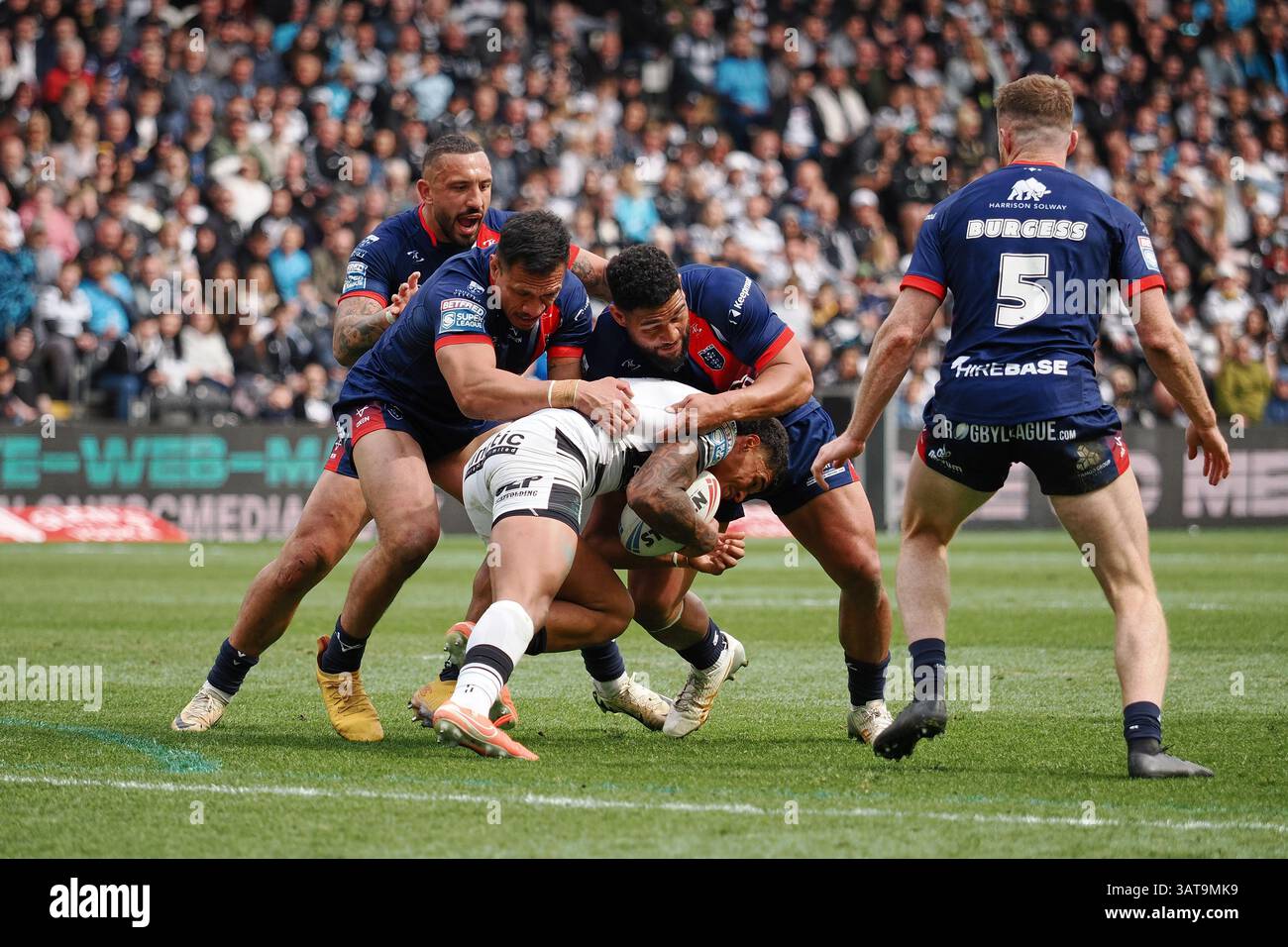 A Hull FC player tries to push forward as HULL KR players defend during ...