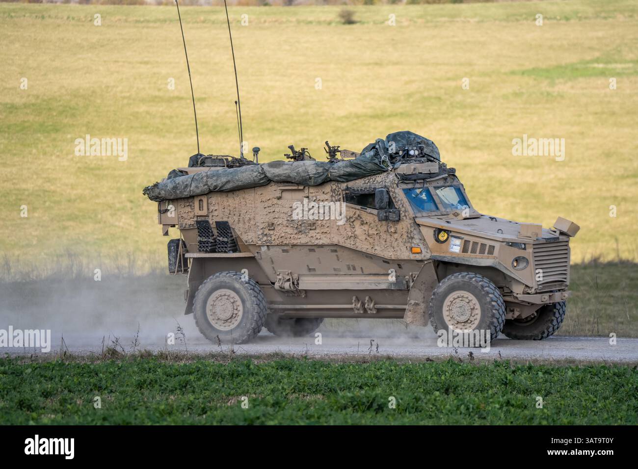 a british army foxhound MRAP vehicle driven at speed on a dusty track ...