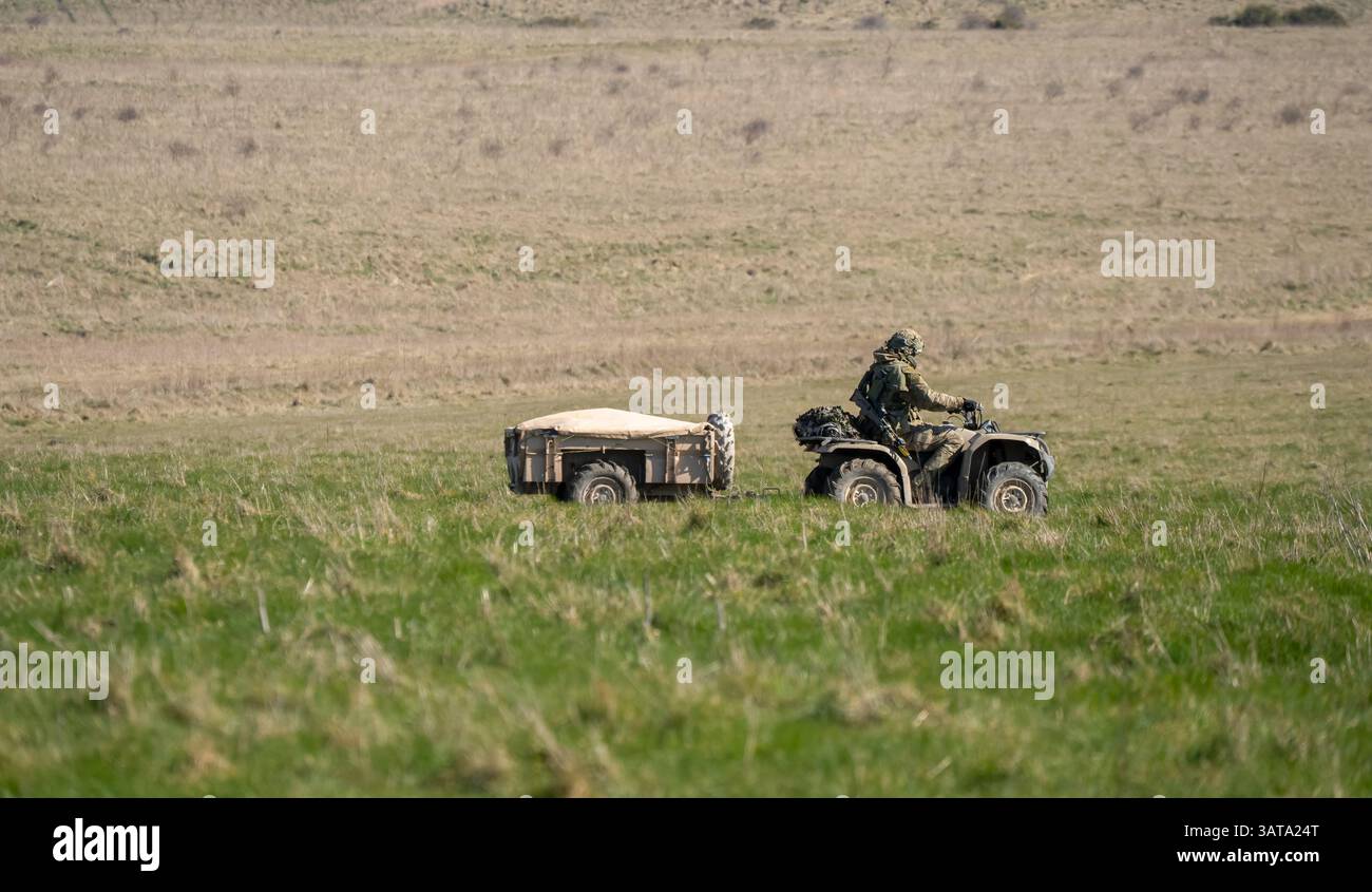 army soldier riding a quad bike with trailer, driving across ...
