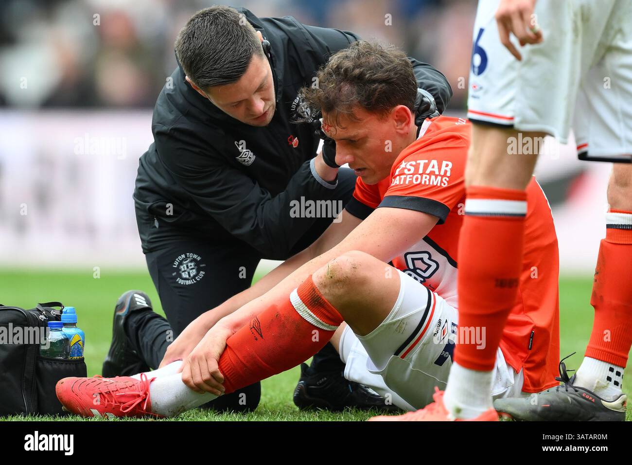 Kal Naismith of Luton Town with a blooded face, gets medical attention ...