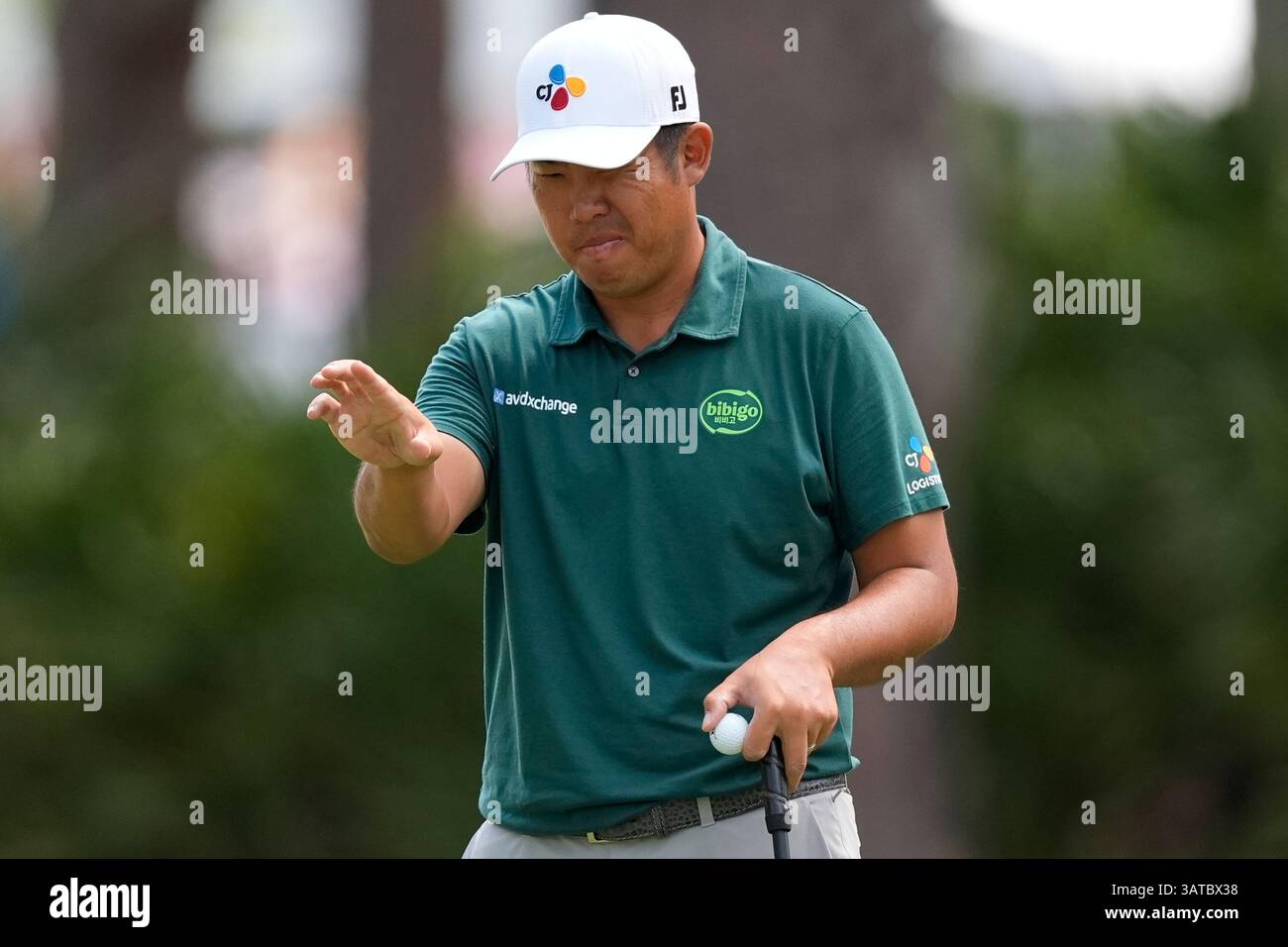 Byeong Hun An, of South Korea, lines up a putt on the seventh green ...