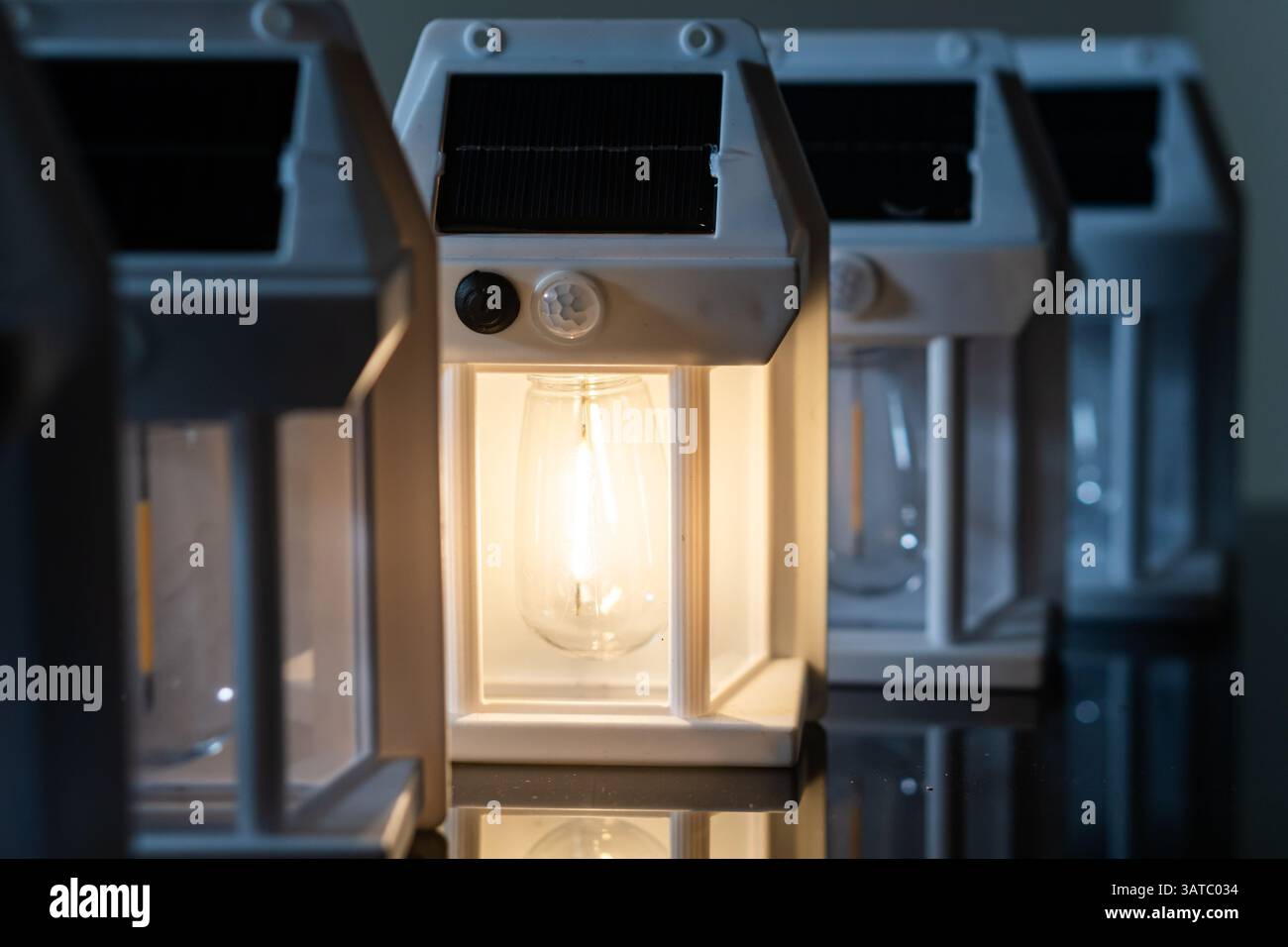 A row of solar-powered lanterns, with one lantern illuminated, casting ...