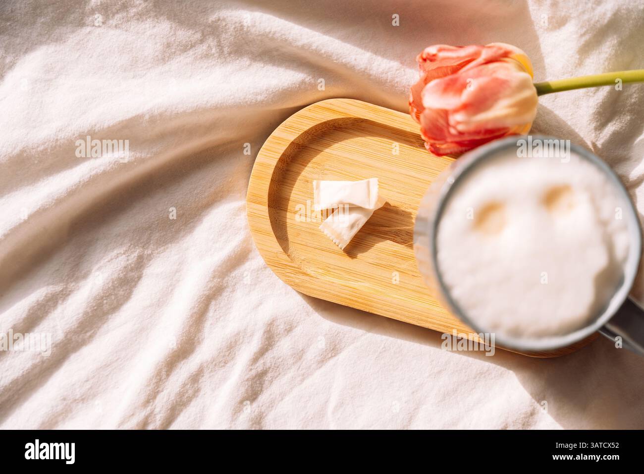 Two pouches of snus next to morning coffee with foam on white bed linen ...
