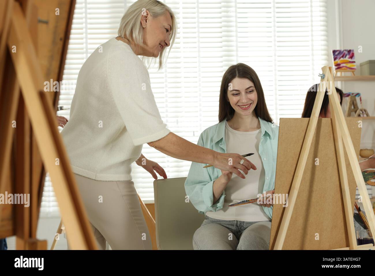 Artist teaching her student to paint in studio Stock Photo - Alamy