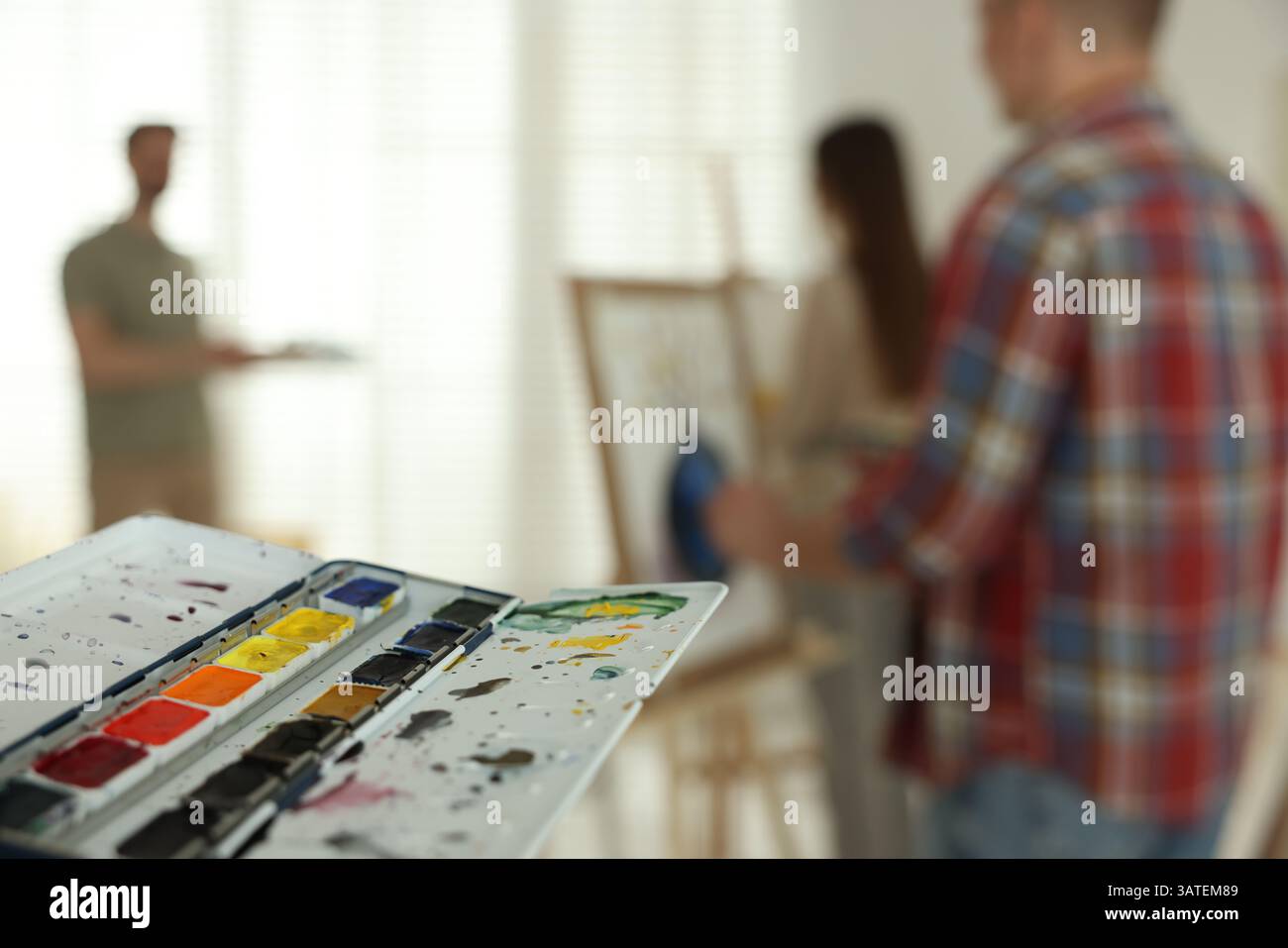 Artist and his students having painting class in studio, focus on color ...