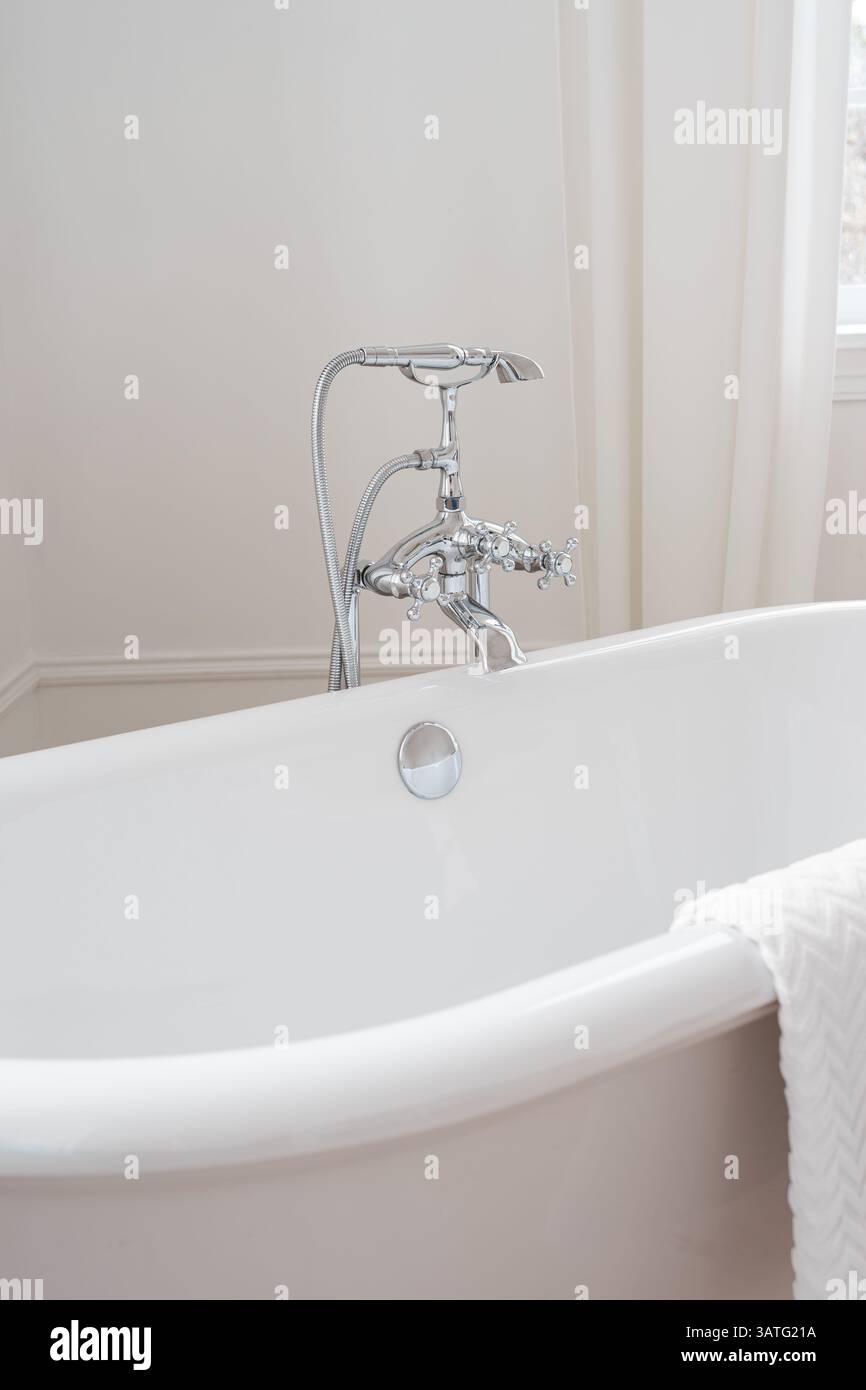 Shiny metal chrome faucet on white freestanding bathtub. Plumbing ...