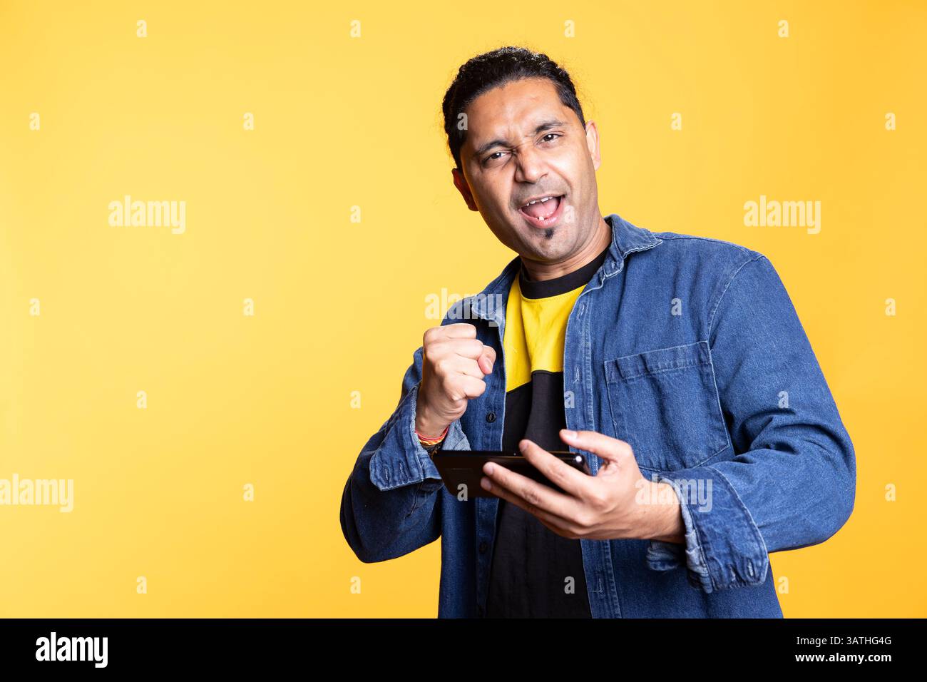 Pleased indian guy cheering after winning game on gaming console ...