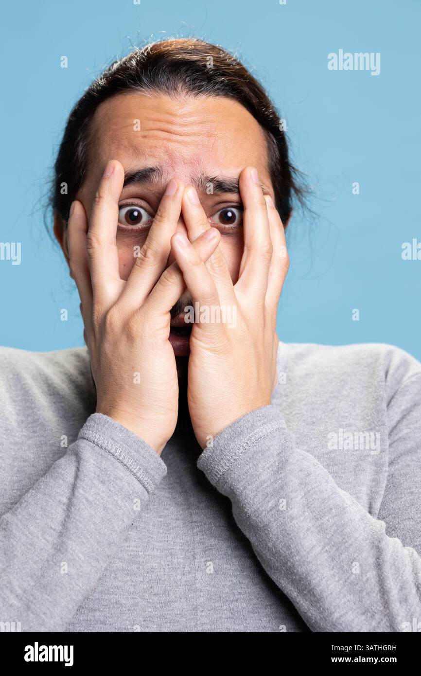 Scared terrified guy feeling extremely afraid about something in studio, showing real anxiety ...