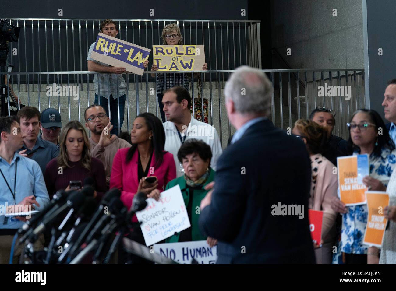 People hold up signs as Sen. Chris Van Hollen, D-Md., speaks during a ...