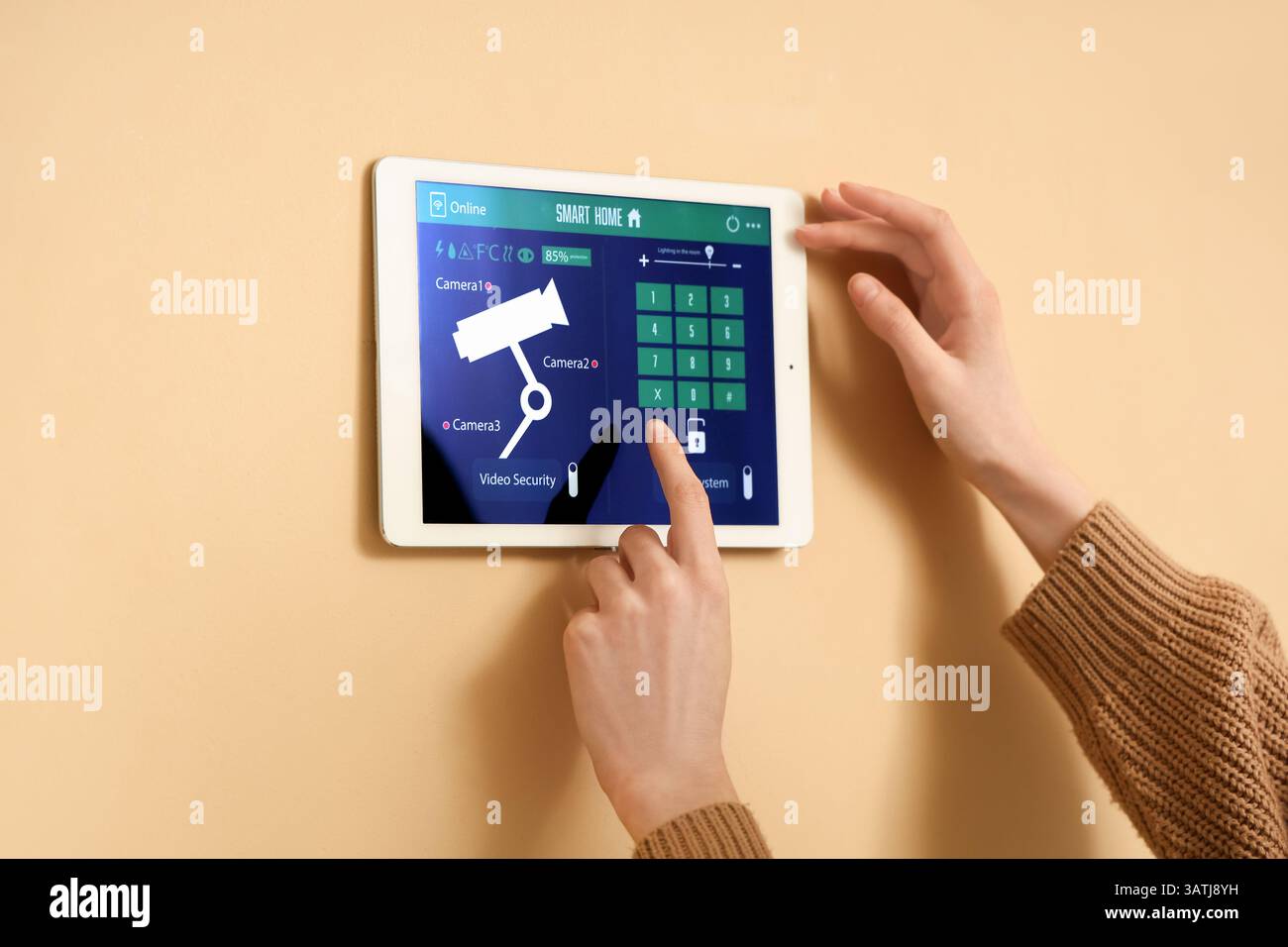 Female hands using smart home security system control panel on beige ...
