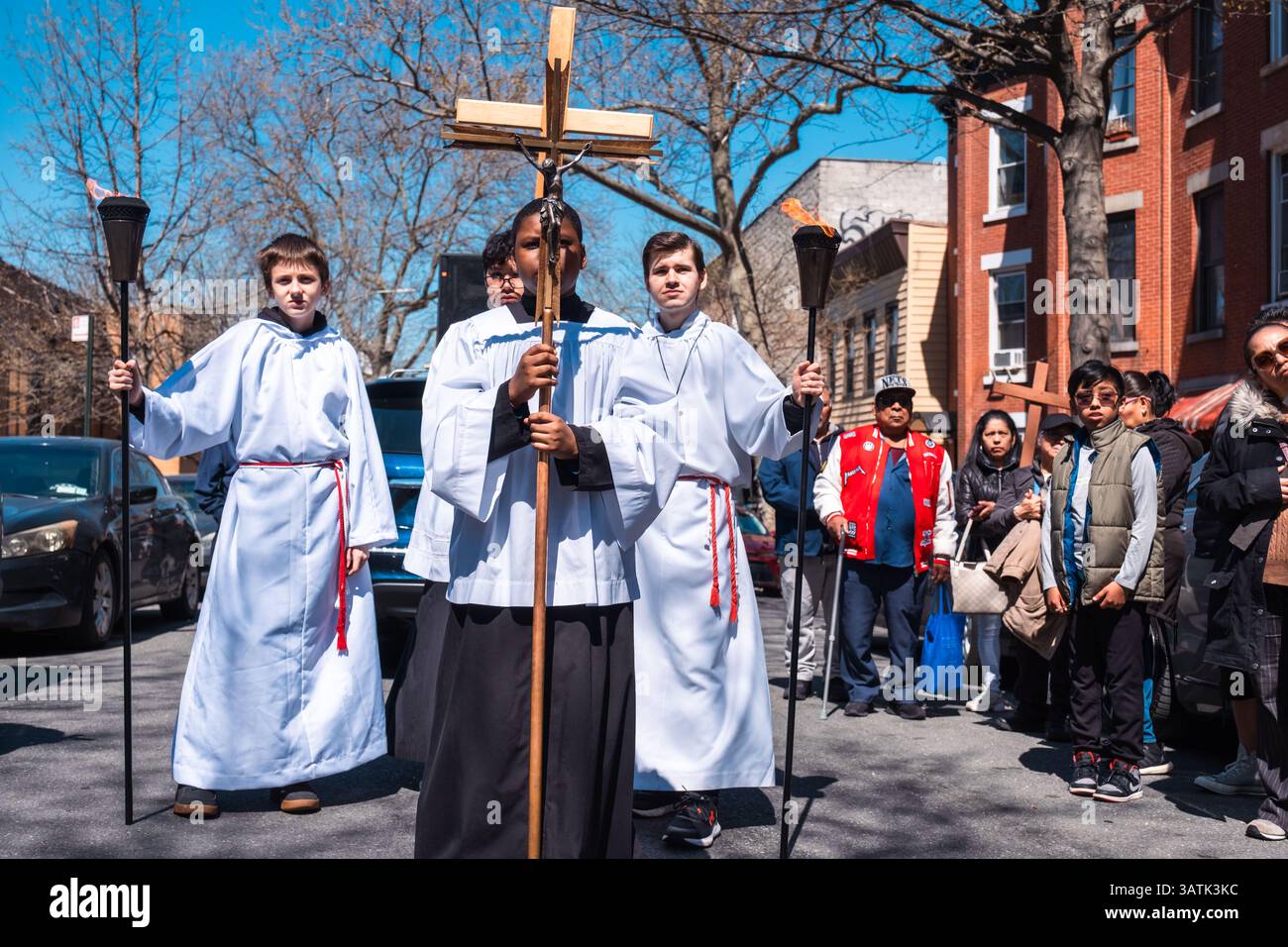 Choir boys, leading the procession, hold torches and a cross ...