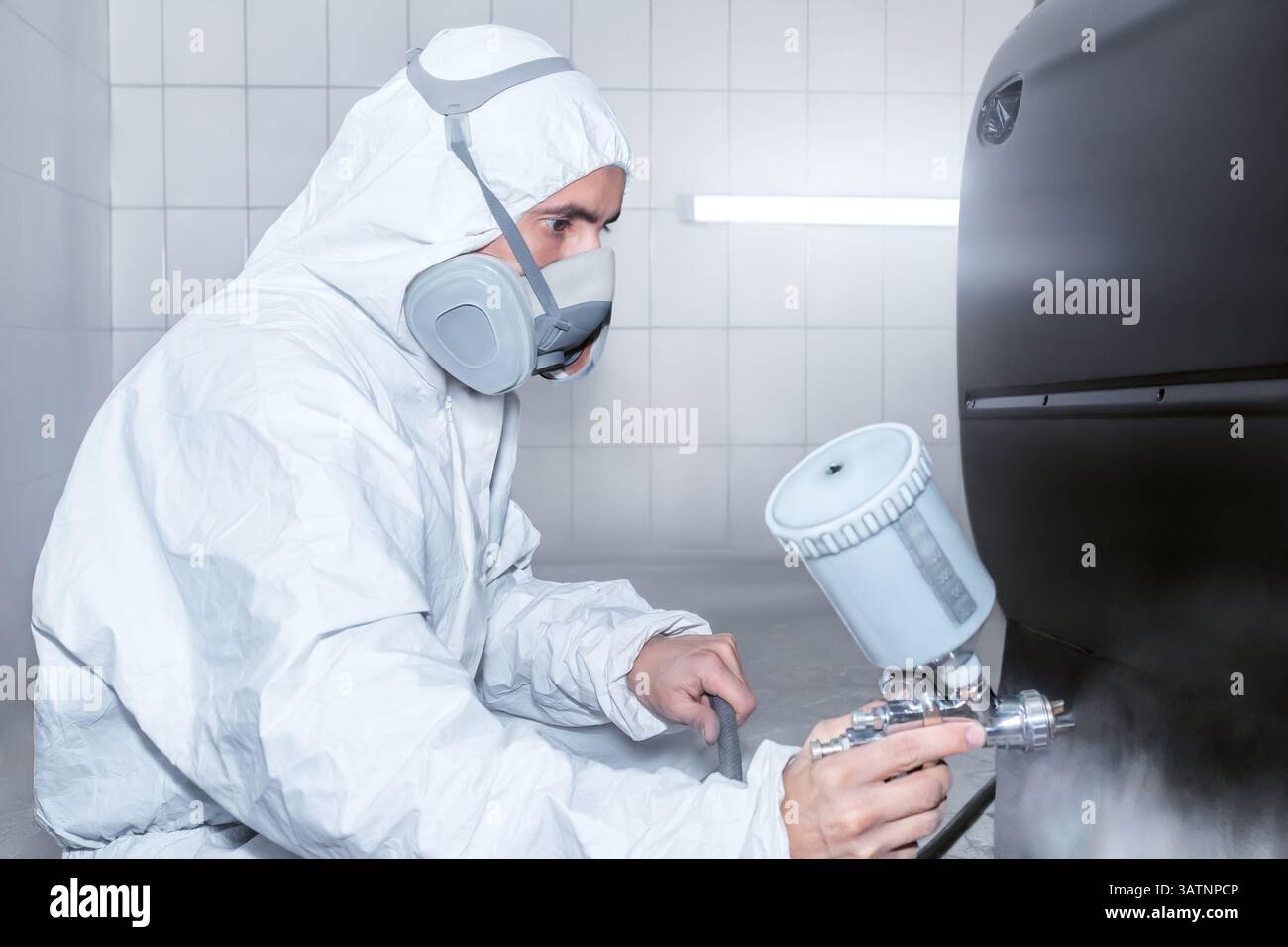 Skilled worker using spray gun to paint car body in workshop. for ...