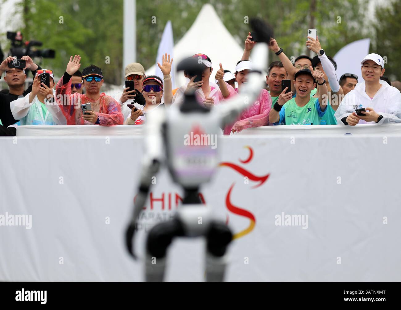 Beijing, China. 19th Apr, 2025. Participants waves to a robotic ...