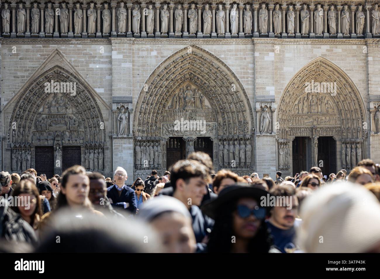 Dozens of catholics stand in front of the Notre-Dame de Paris Cathedral ...