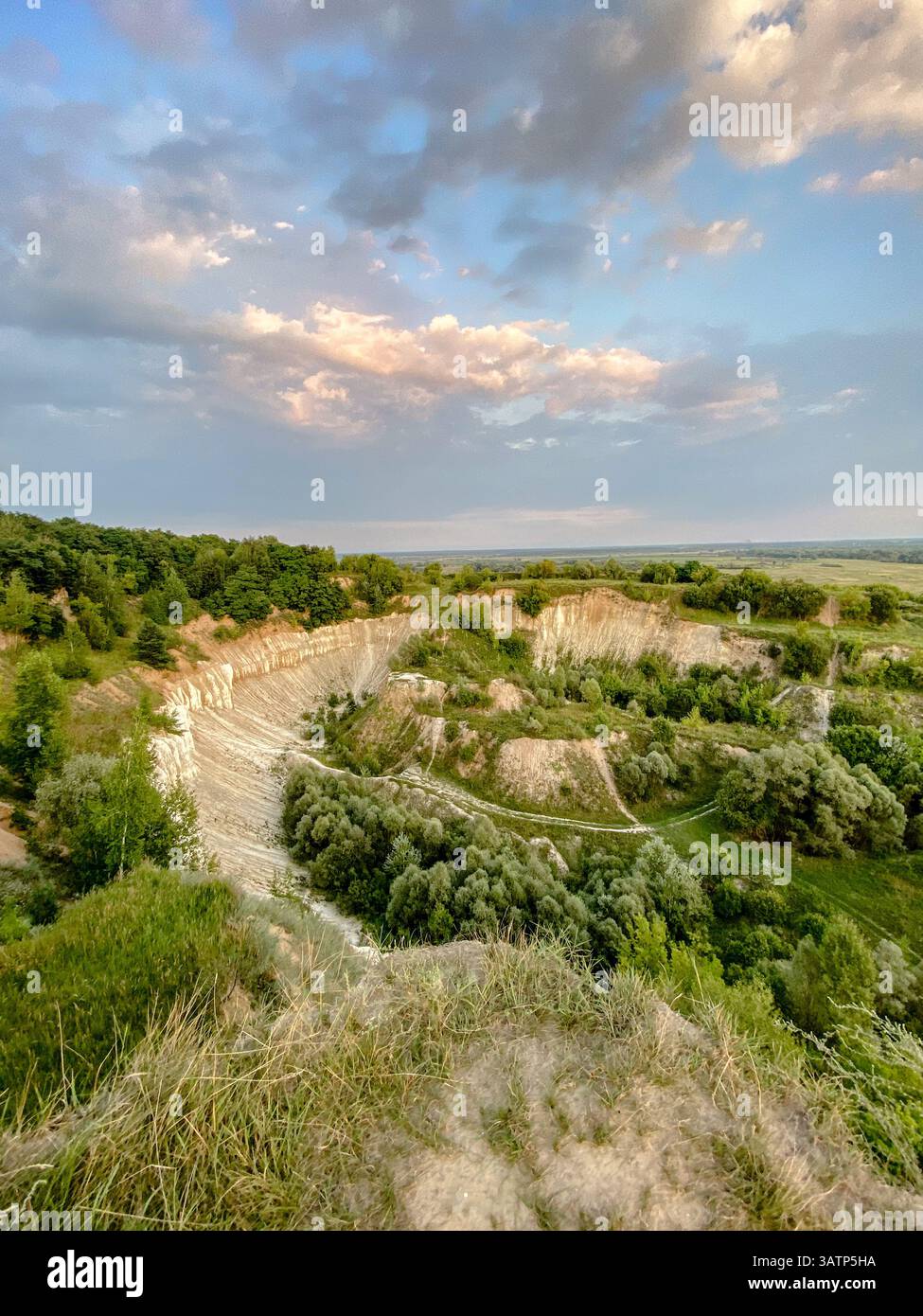 Chalk quarry surrounded by greenery with dramatic sunset sky in rural ...