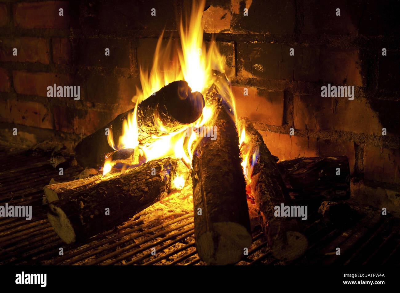 Burning round logs in fireplace against brick smoked wall Stock Photo ...