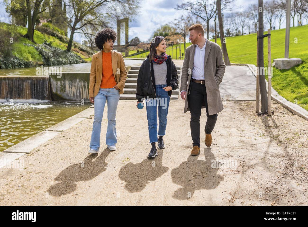 Three young professionals are enjoying a walk and conversation together ...