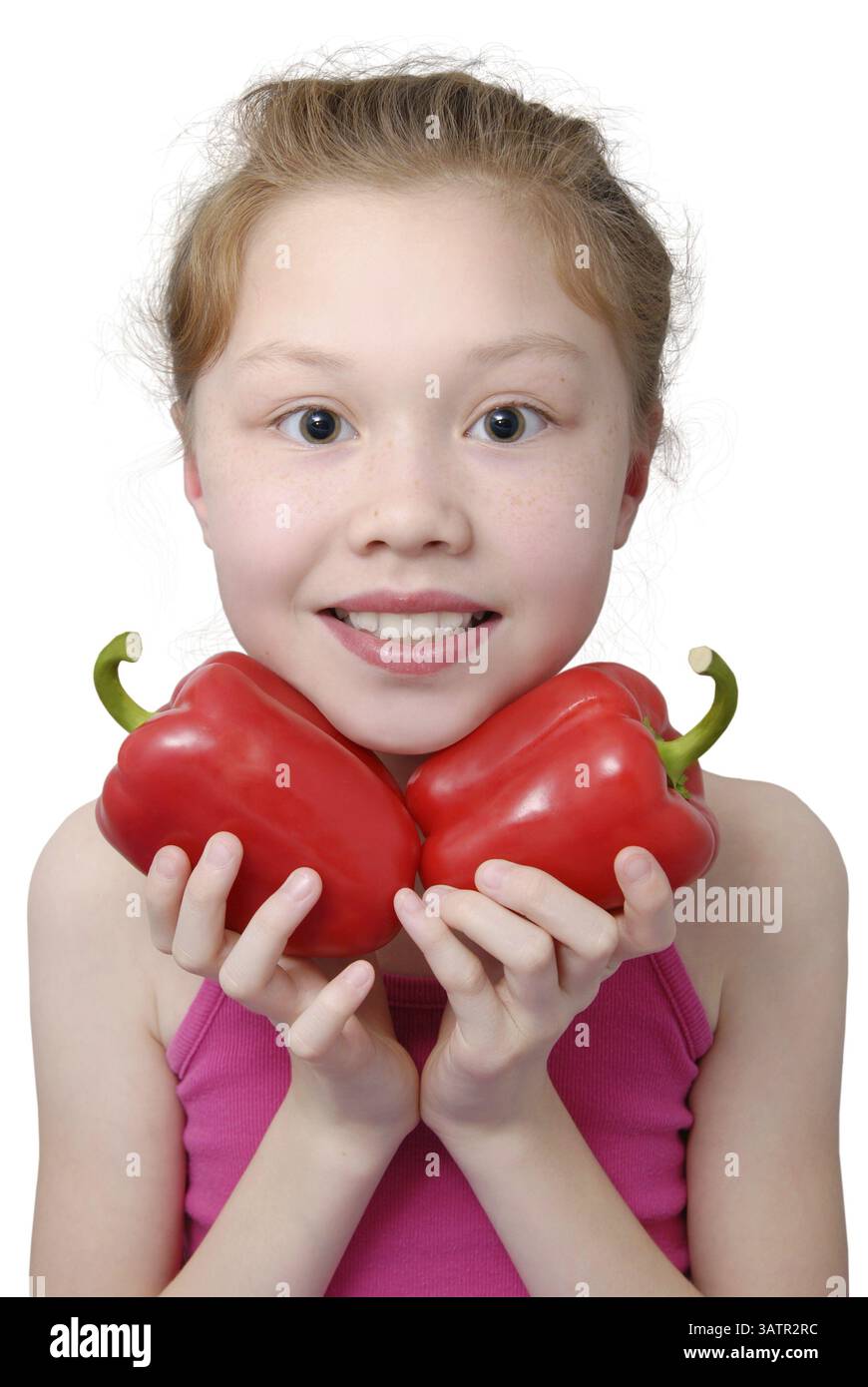 Smiling eight year old girl holds two red peppers at her face Stock ...