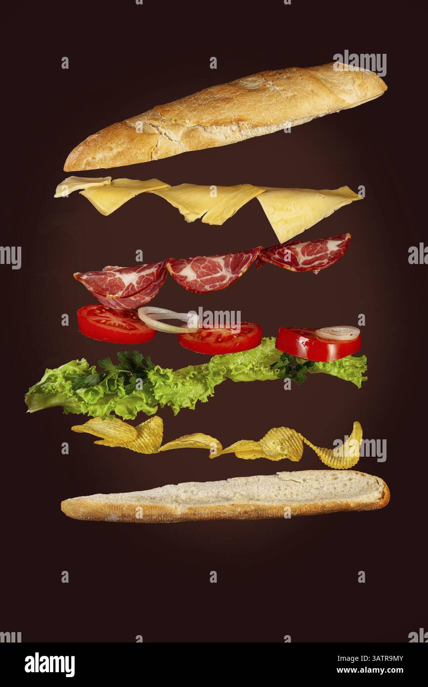 Big sandwich with flying cheese, ham and greenery on a studio ...